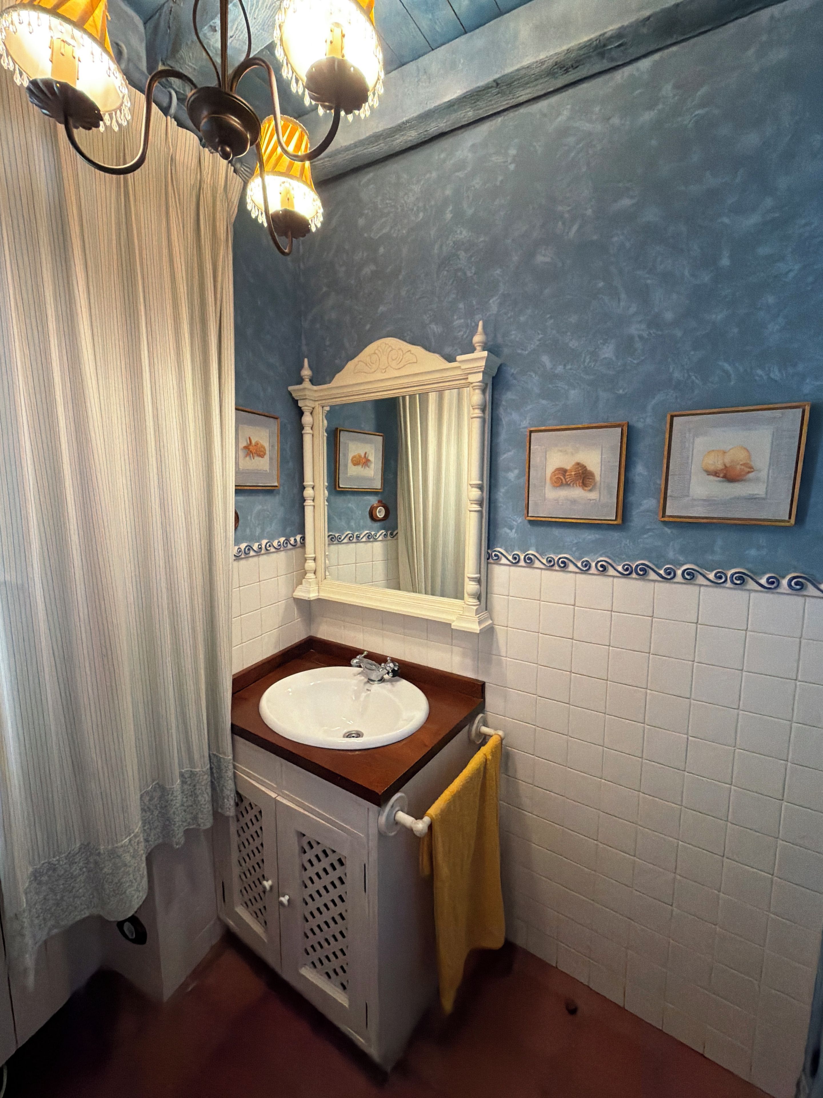 Casa de banho com lavatório, espelho e fotografias emolduradas na parede.