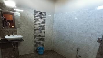 Casa de banho com lavatório, espelho, chuveiro e sanita.
