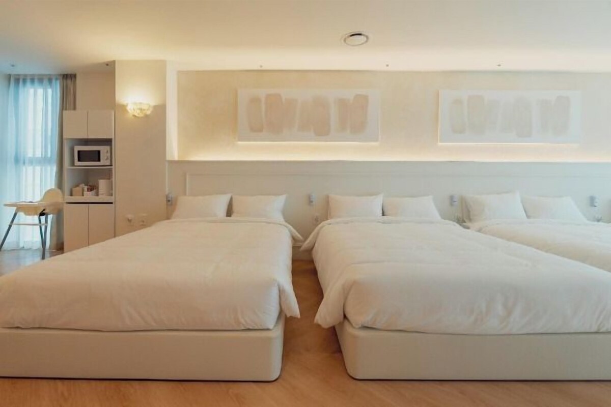 Quarto de hotel com duas camas, uma escrivaninha e uma cadeira.