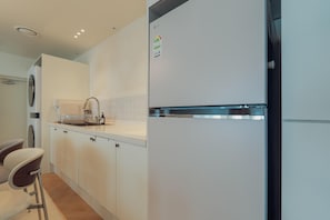 Cozinha moderna com armários brancos, geladeira de aço inoxidável e forno embutido.