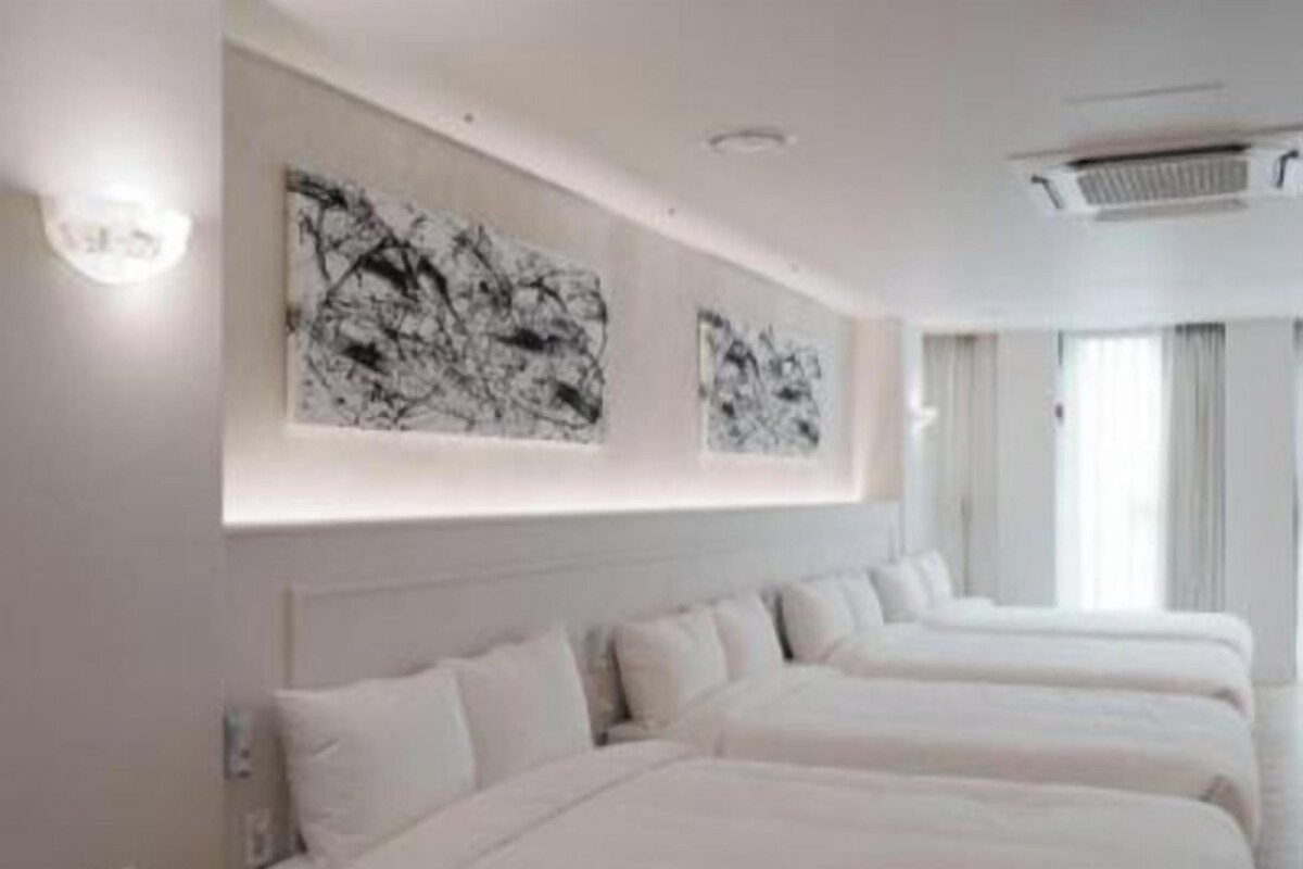 Quarto de hotel com uma cama grande, cabeceira e duas obras de arte penduradas na parede.