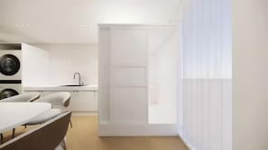 Quarto moderno e minimalista com mesa de jantar, cozinha planejada e porta deslizante para outro espaço.