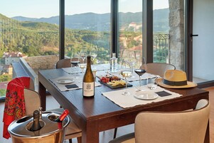Mesa de jantar posta para dois, com taças de vinho, uma garrafa de vinho e um prato de aperitivos.