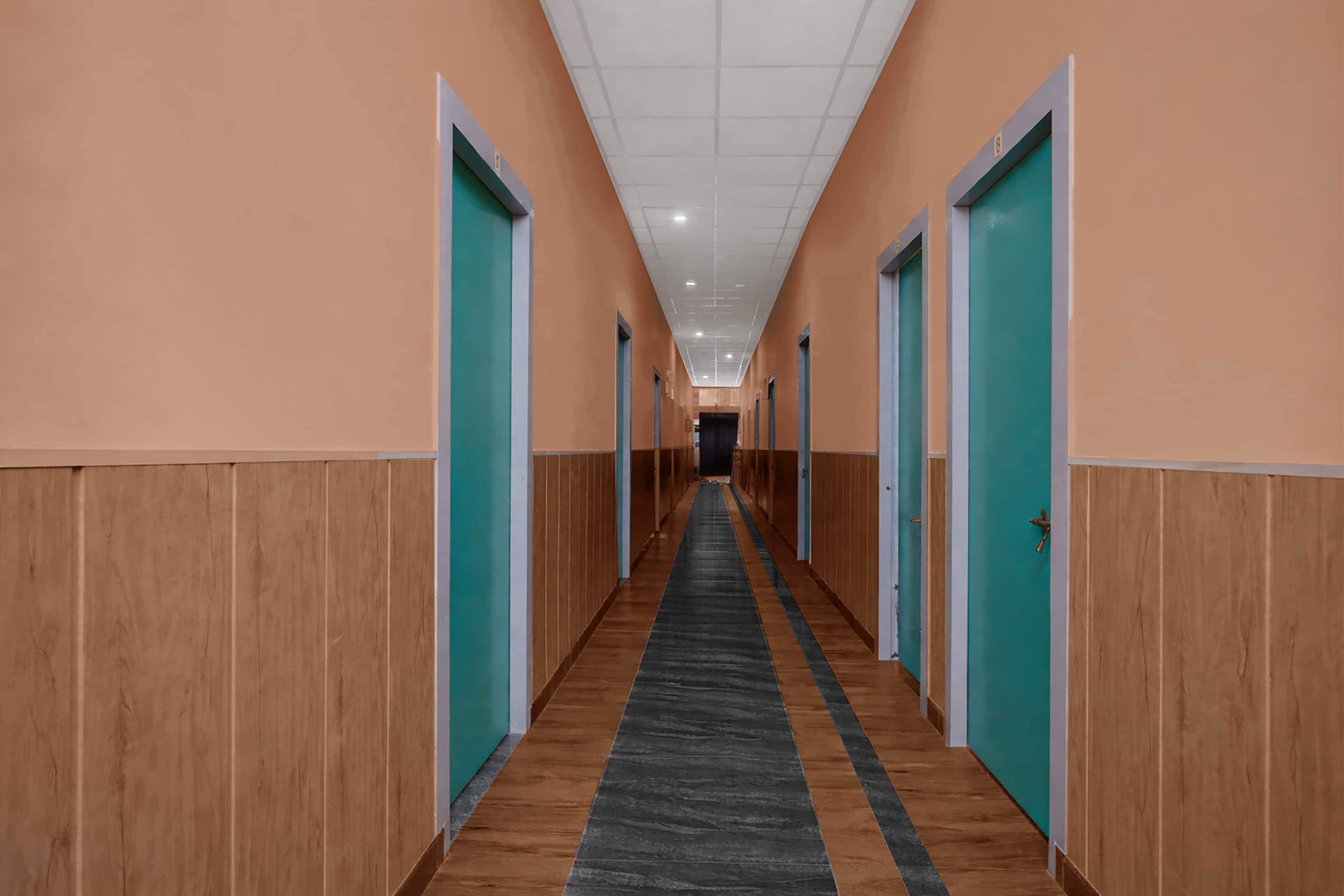 Um corredor extenso com portas em ambos os lados, dando acesso a quartos individuais.