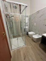 Uma casa de banho com chuveiro em cabine de vidro, lavatório branco e bidé.