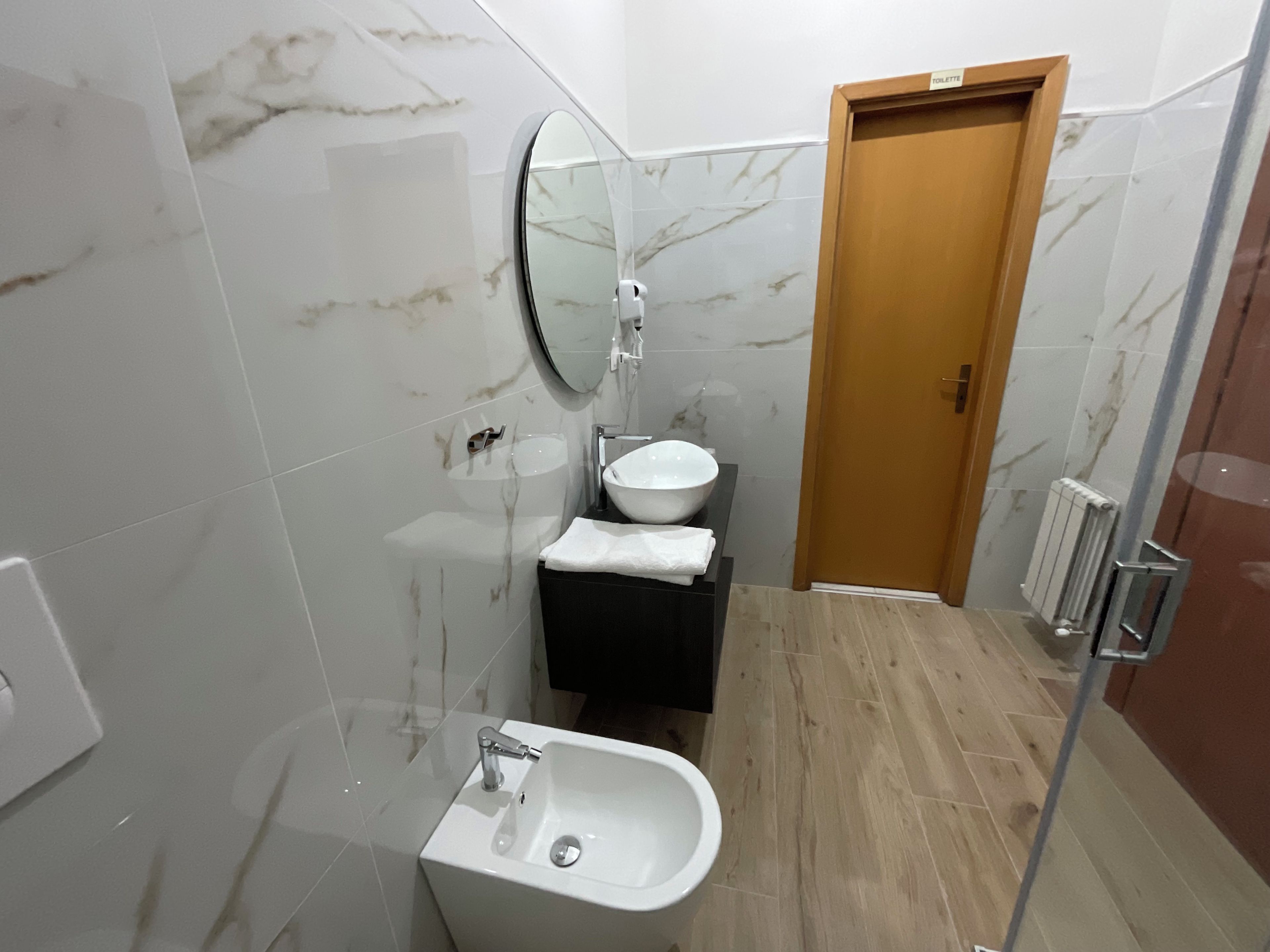 Casa de banho moderna com lavatório branco, espelho e sanita.
