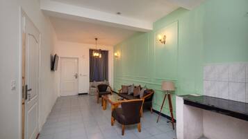 Uma sala de estar com sofá, cadeiras, mesa de centro e abajur.