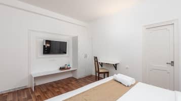 Quarto de hotel com cama, escrivaninha, cadeira, guarda-roupa e janela.