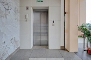 Um elevador com um visor digital, uma placa de elevador acima e uma parede com desenhos abstratos de linhas.