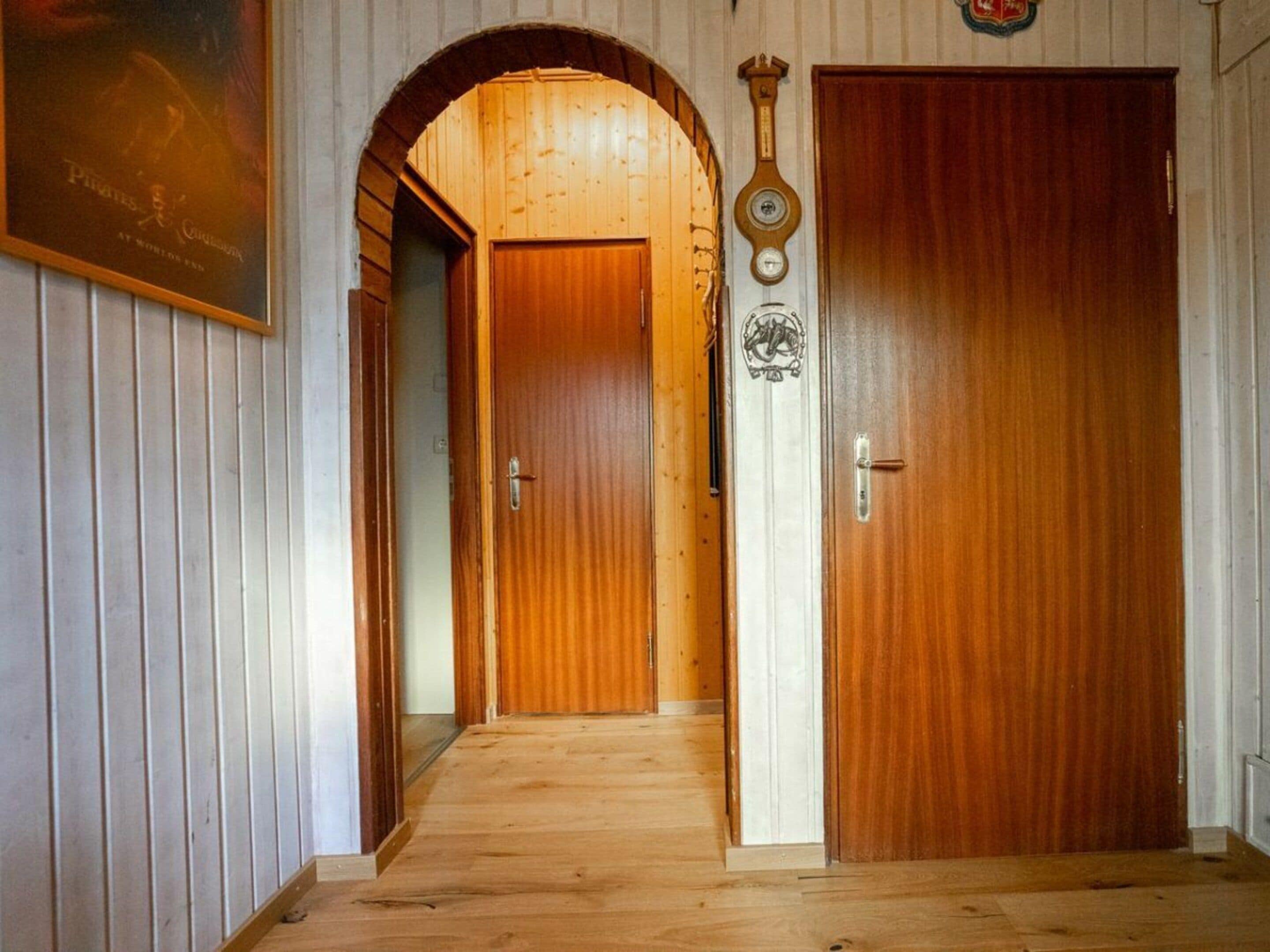 Um corredor com portas e piso de madeira.