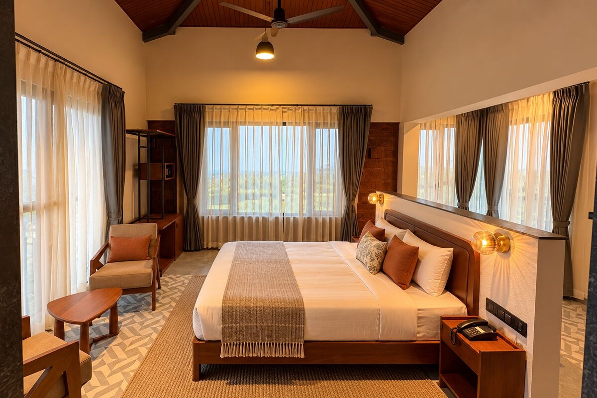 Quarto de hotel com uma cama grande, uma escrivaninha, uma cadeira e vista para o exterior.