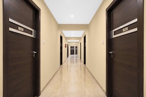 Corredor de hotel com portas de madeira escura, numeradas 105 e 104, que dão para os quartos.