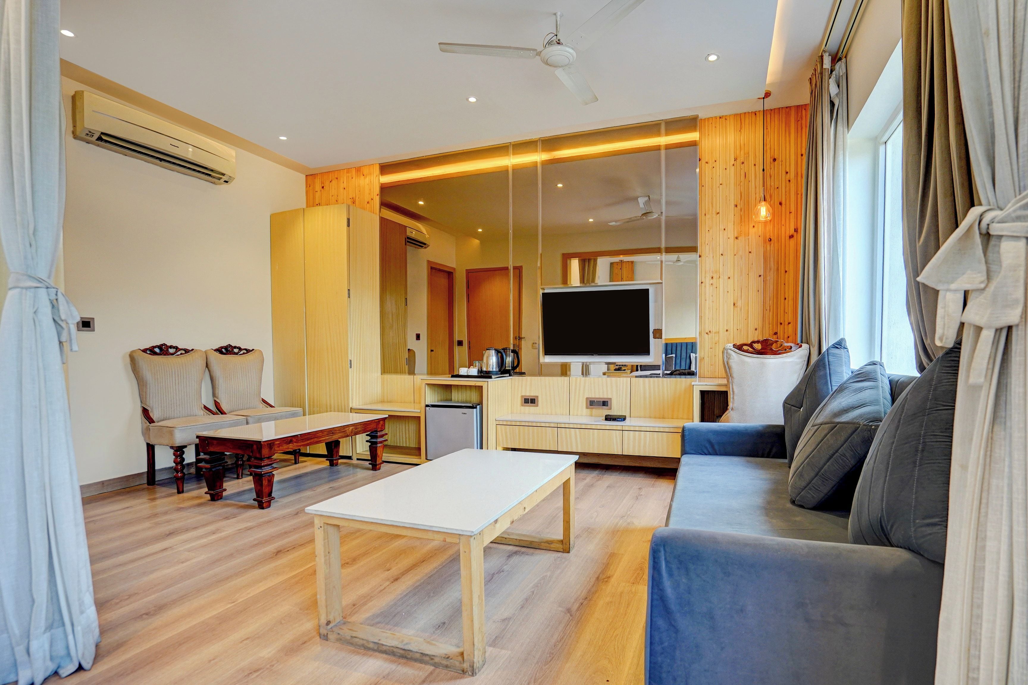 Uma sala de estar moderna com sofá, mesa de centro, televisão e cozinha com armários de madeira.