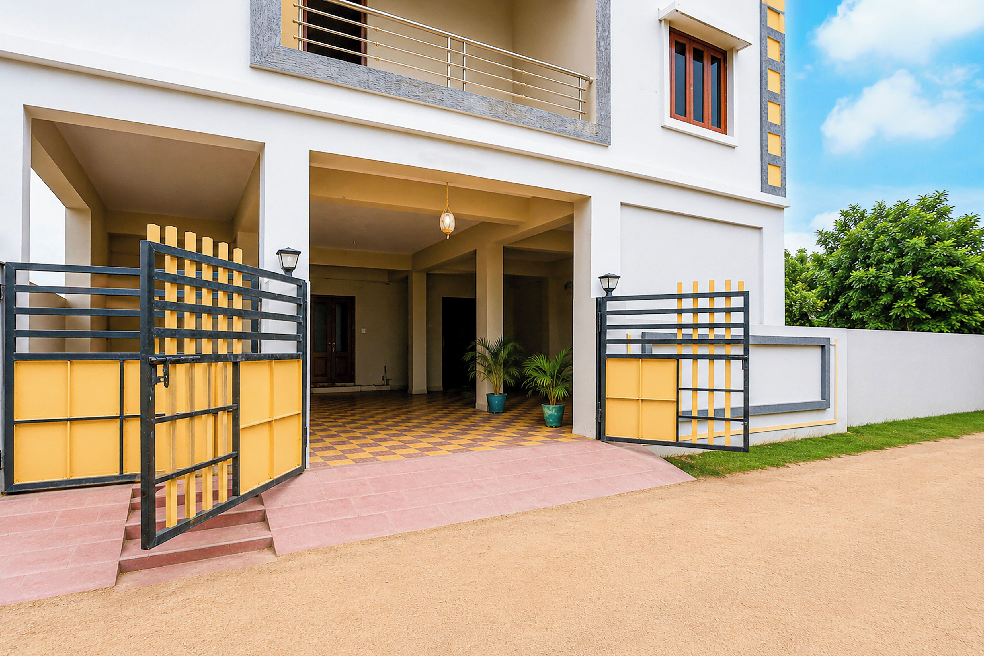 Um edifício residencial de dois andares com chão xadrez, varanda e portão fechado.