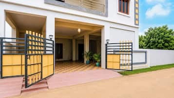 Um edifício residencial de dois andares com chão xadrez, varanda e portão fechado.