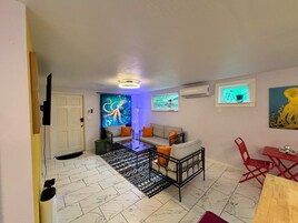 Uma sala de estar com sofá, mesa de centro e mesa de jantar com cadeiras.