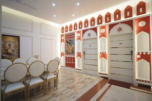 Um quarto com uma fileira de cadeiras, uma estátua de Buda e uma parede com motivos tradicionais indianos.