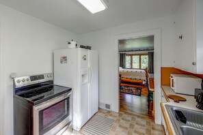 Cozinha compacta com fogão, geladeira e micro-ondas.