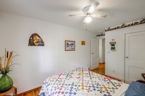 Quarto com cama, ventilador de teto, porta e parede com moldura decorativa.