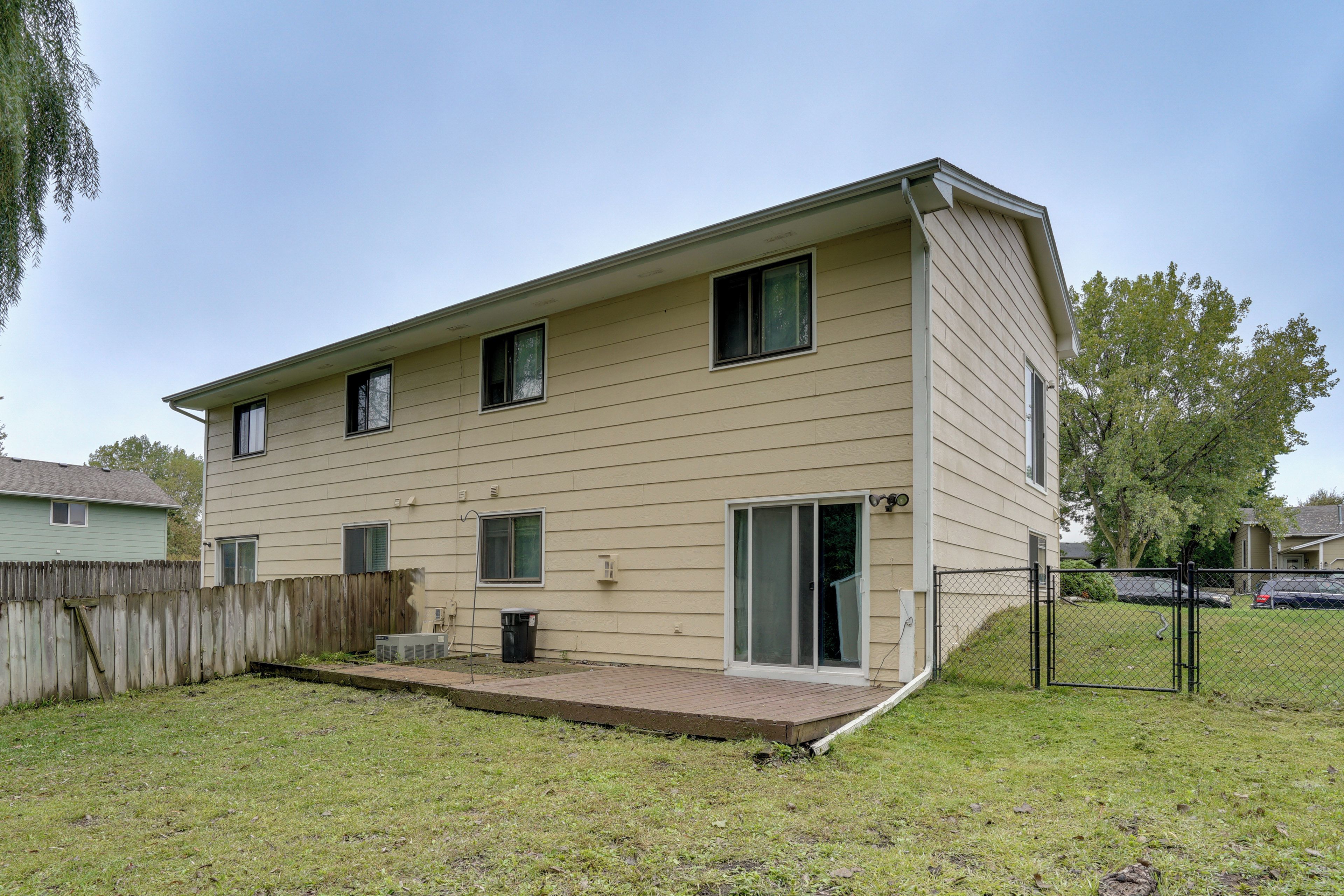 Um edifício residencial de dois andares com teto plano, varanda frontal e quintal cercado.