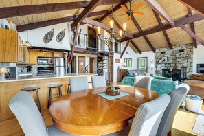 Cozinha espaçosa com eletrodomésticos modernos, sala de jantar com mesa de madeira e lareira de pedra na sala de estar.