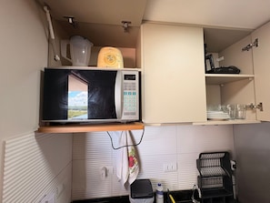 Cozinha equipada com micro-ondas, bebedouro e pia.