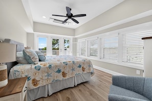 Quarto com cama, ventilador de teto, janela com persianas e vista para o exterior.
