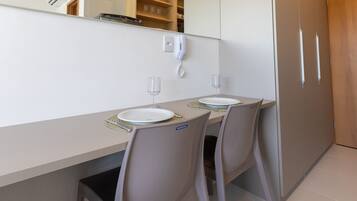 Quarto de hotel com mesa de jantar, duas cadeiras, telefone e minibar.