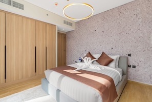 Quarto moderno com cama, almofadas, roupão e armário.