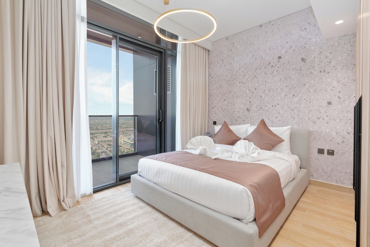 Quarto de hotel moderno com uma cama grande, vista através de uma porta de correr e luminária no teto.