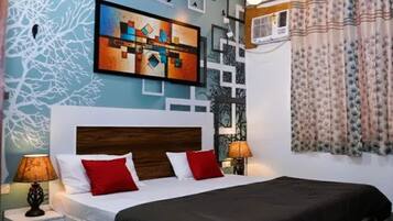 Quarto de hotel com cama, duas luminárias de cabeceira, parede com pintura geométrica e janela com cortinas.