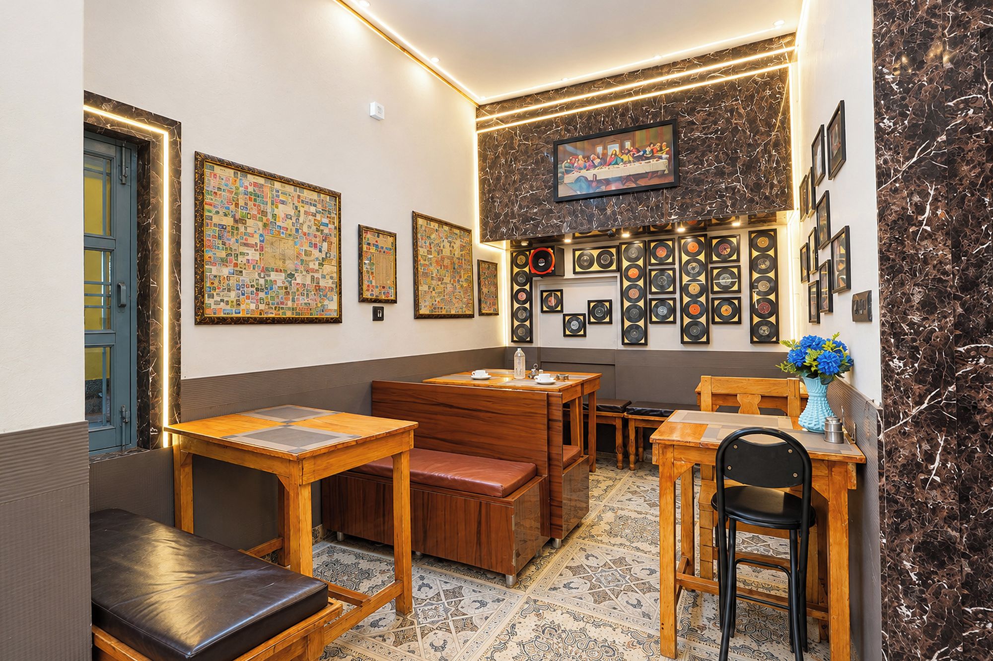 Um restaurante acolhedor com mobiliário de madeira, uma parede de mármore com obras de arte emolduradas e um quadro grande sobre o balcão.