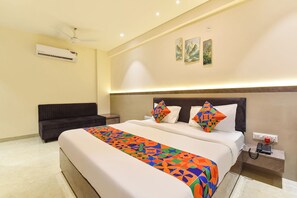 Quarto de hotel com cama, sofá, ar condicionado e obras de arte na parede.