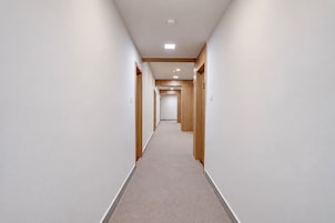 Um corredor com piso carpetado, painéis de madeira nas paredes e iluminação embutida.