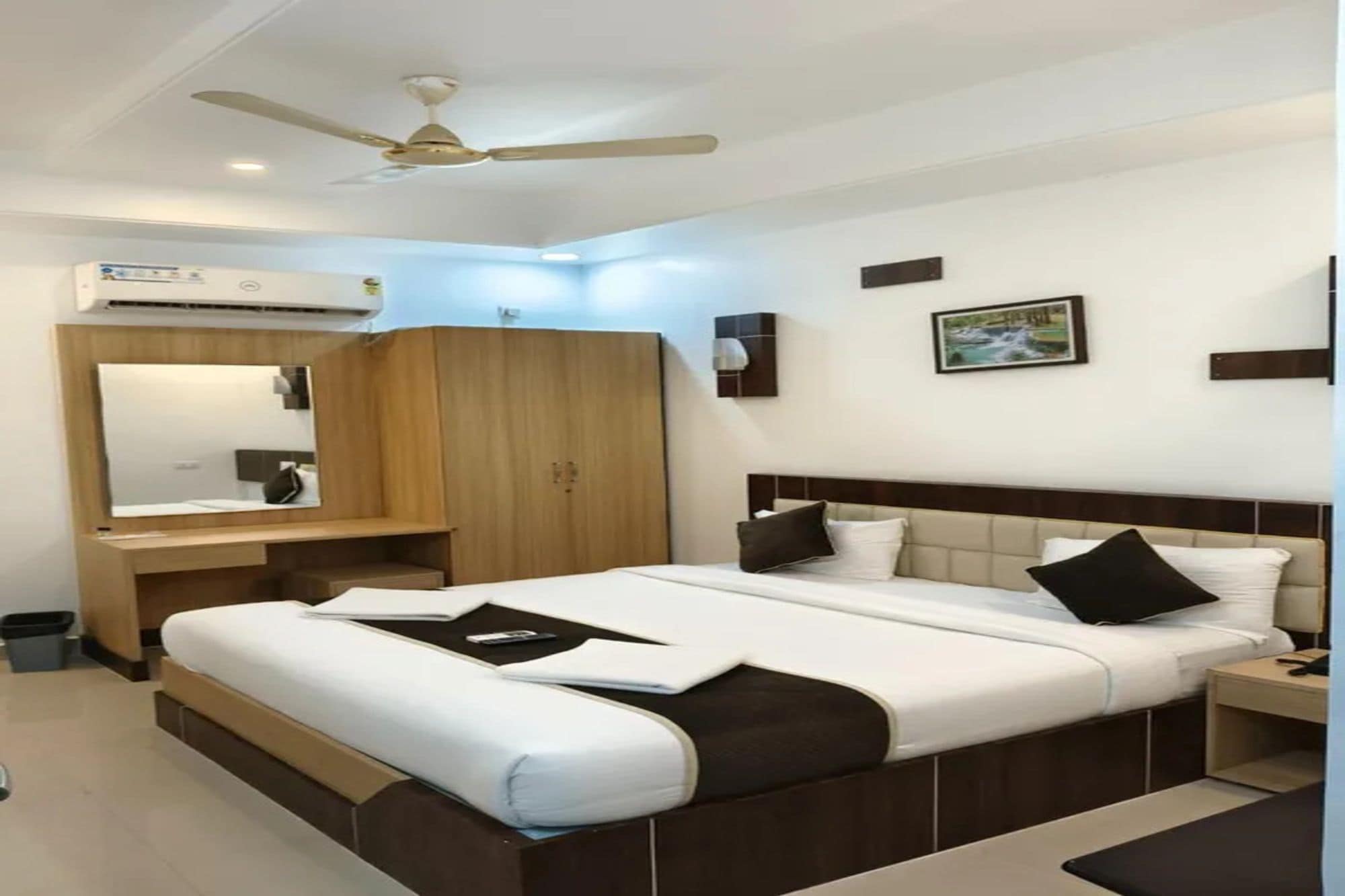 Quarto de hotel com cama, guarda-roupa, escrivaninha e ventoinha no teto.
