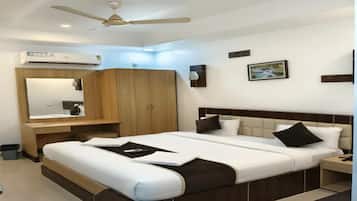 Quarto de hotel com cama, guarda-roupa, escrivaninha e ventoinha no teto.