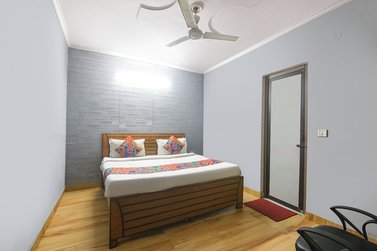 Quarto com cama, ventoinha no teto, porta e tapete vermelho.