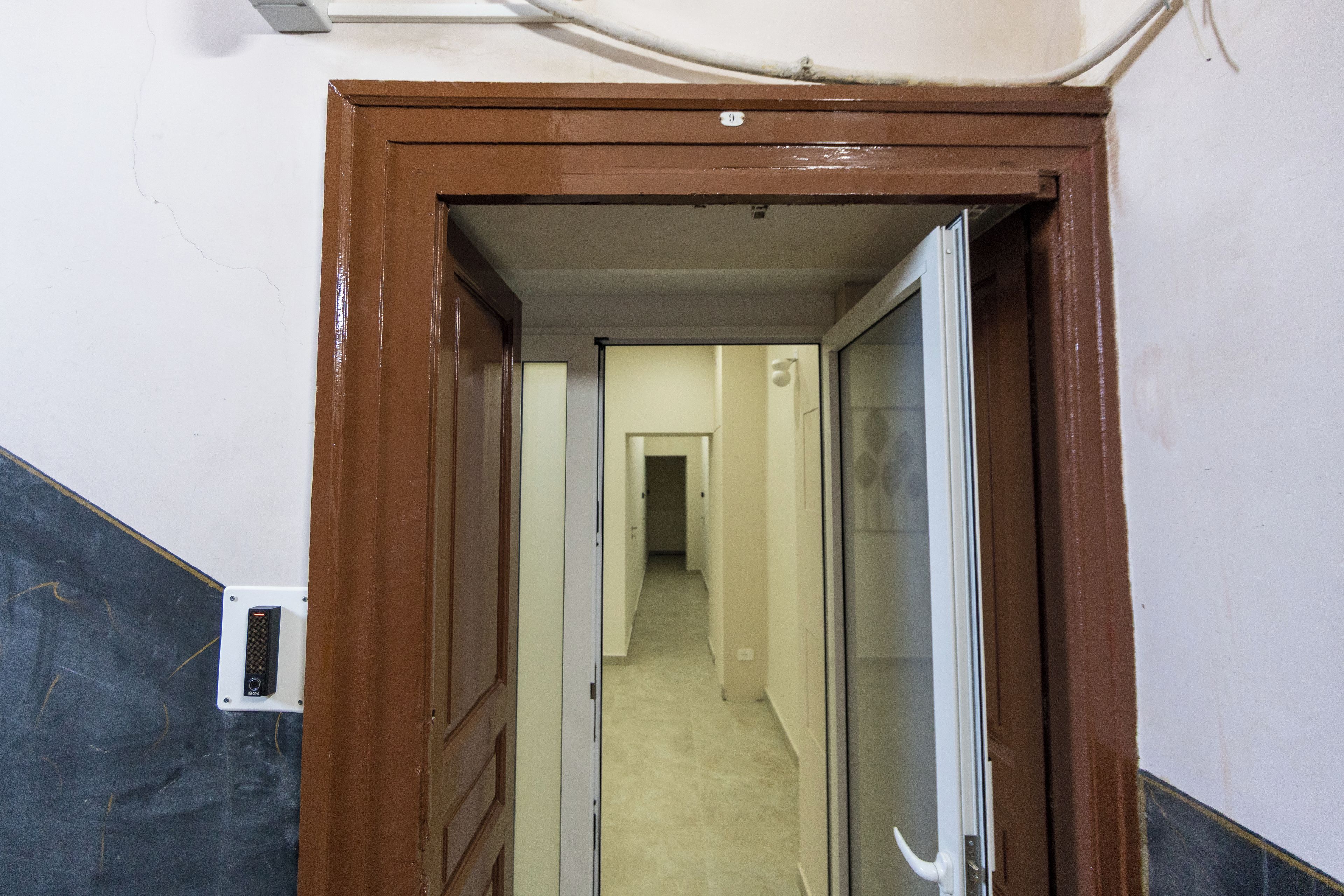 Um corredor com moldura de porta marrom, porta branca e parede branca com interruptor de luz.