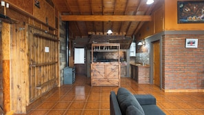 Um interior rústico com vigas de madeira, lareira, cozinha e área de estar.