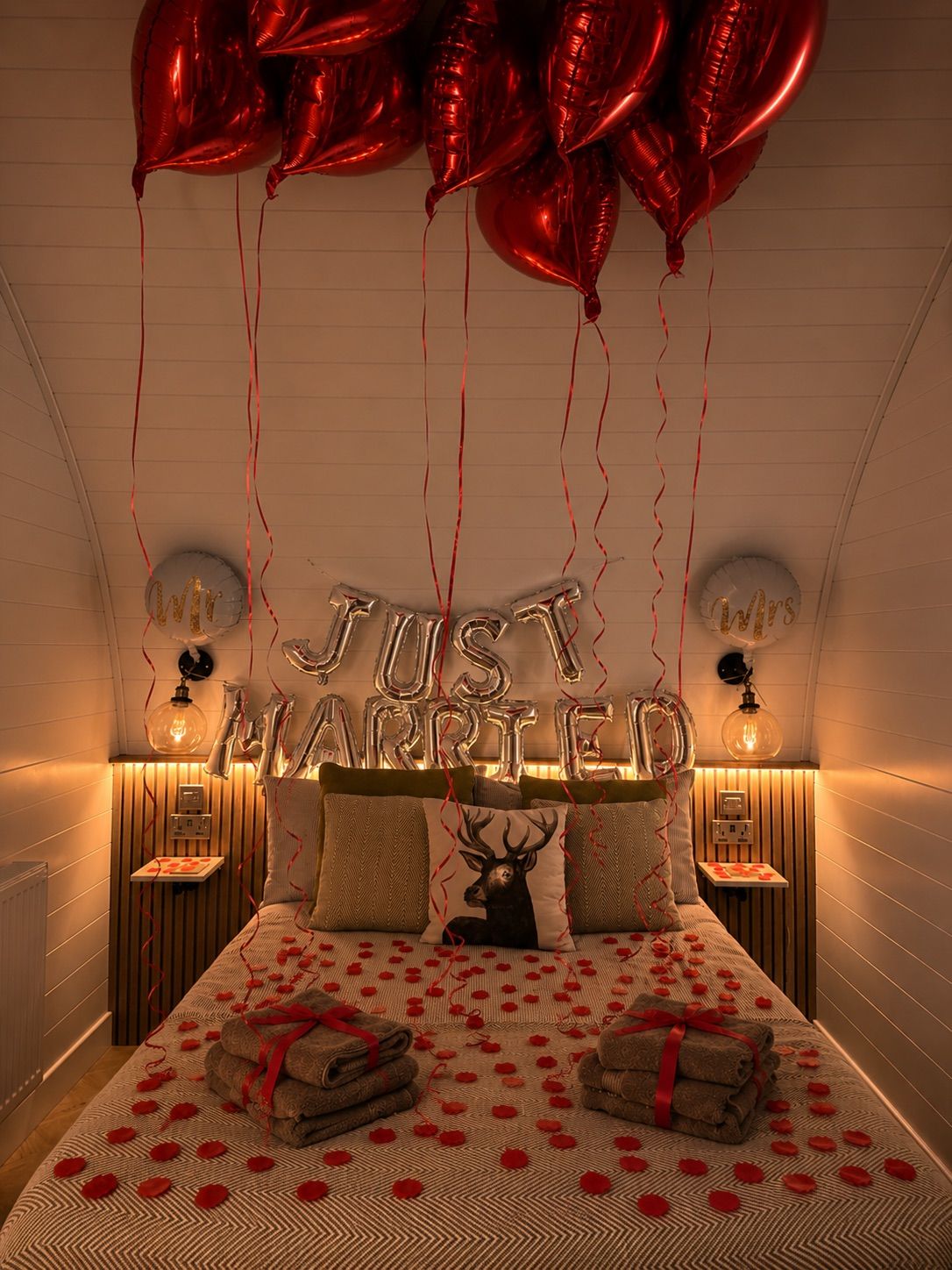 Quarto com cama, travesseiros e placa com a inscrição 'Just Married'.