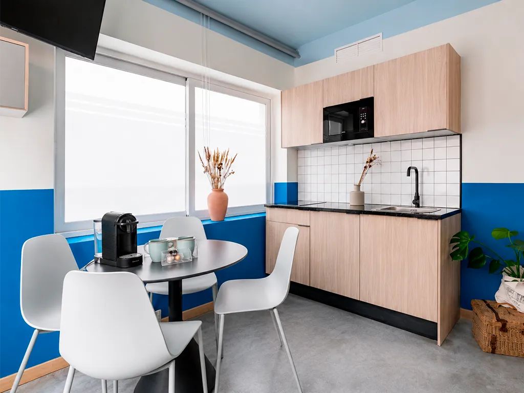 Cozinha compacta com área de refeições, micro-ondas, pia e janela com vista.