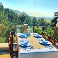 Mesa posta para quatro pessoas com vista para uma paisagem montanhosa.