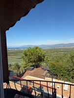 Varanda com vista para a paisagem costeira, incluindo uma árvore e uma cidade ao longe.