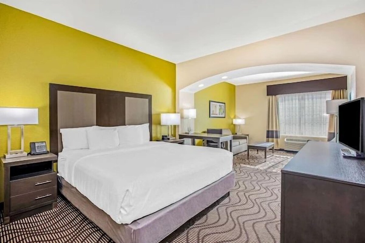Quarto de hotel com uma cama grande, mesas de cabeceira, escrivaninha e televisão.