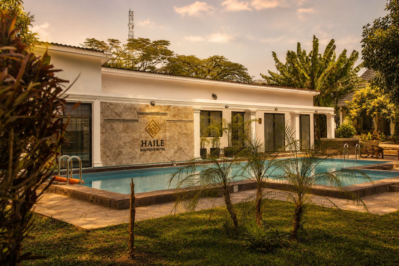 Um hotel boutique com piscina, área de estar externa e um jardim bem cuidado.