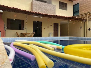 Uma piscina com boias coloridas e um espaço coberto com varanda.