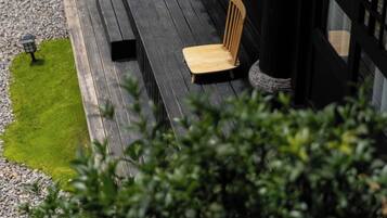 Um deck de madeira com uma única cadeira, um pequeno objeto preto e um poste de luz.