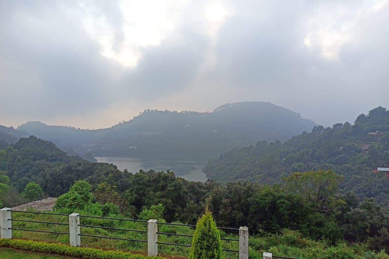 Paisagem acidentada com um lago e uma cerca em primeiro plano.