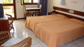 Quarto de hotel com duas camas, uma escrivaninha e cadeiras.