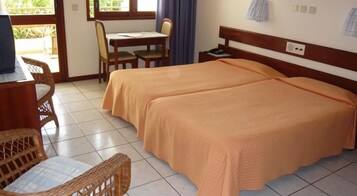 Quarto de hotel com duas camas, uma escrivaninha e cadeiras.